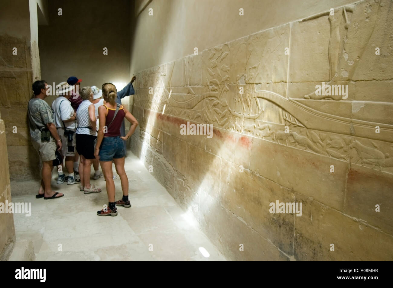 Tourists study ancient inscriptions inside a tomb at the Pyramid ...
