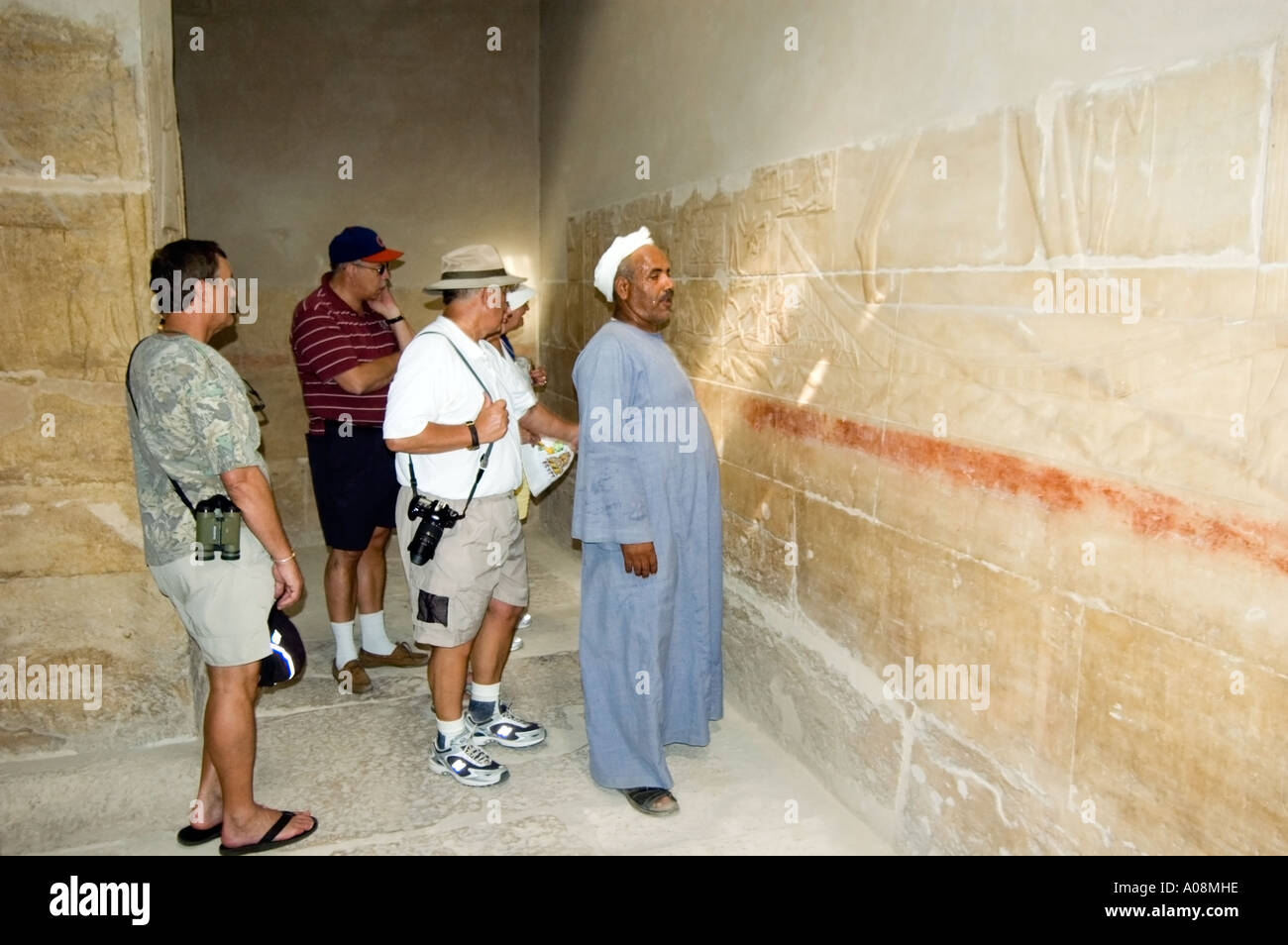 Tourists study ancient inscriptions inside a tomb at the Pyramid ...
