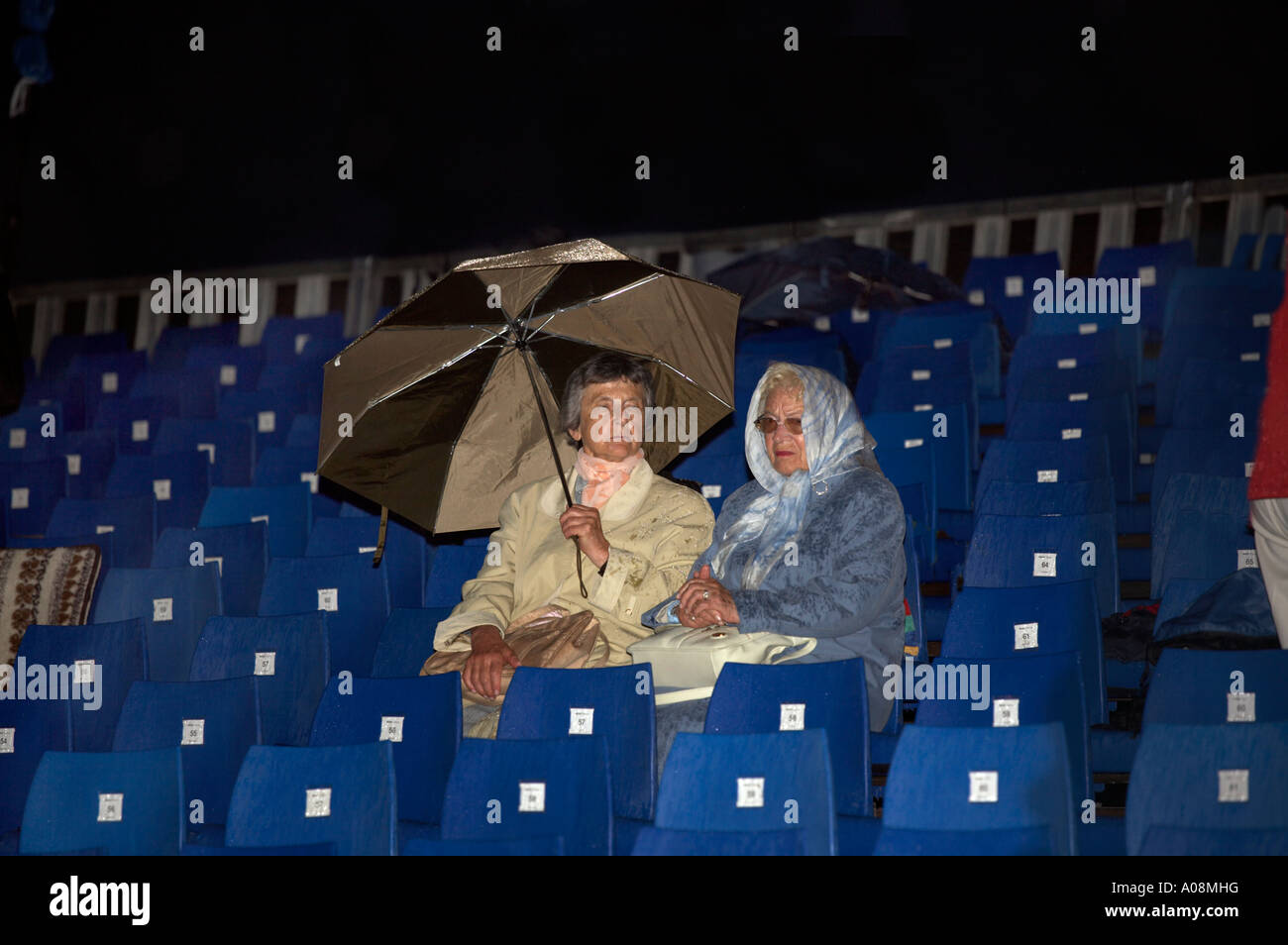 People in the rain at an outdoor cultural event at night Stock Photo ...