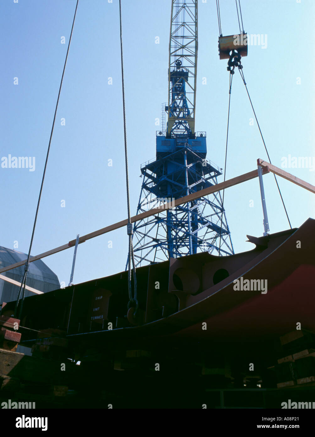 Large crane positioning a section of the keel of a ship on a shipyard ...
