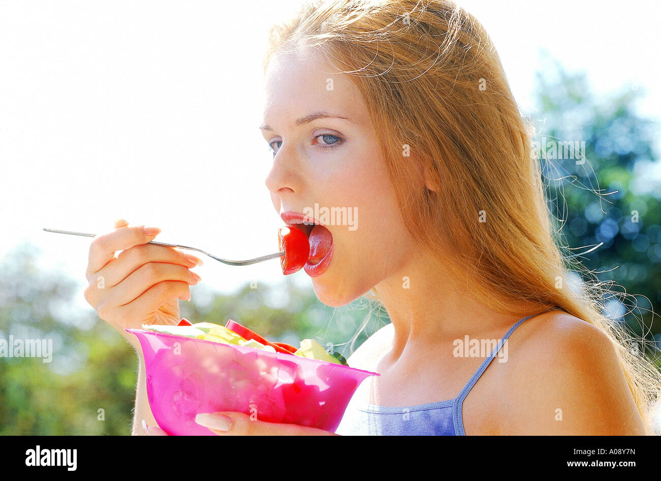 Side profile of a young woman eating salad Stock Photo - Alamy