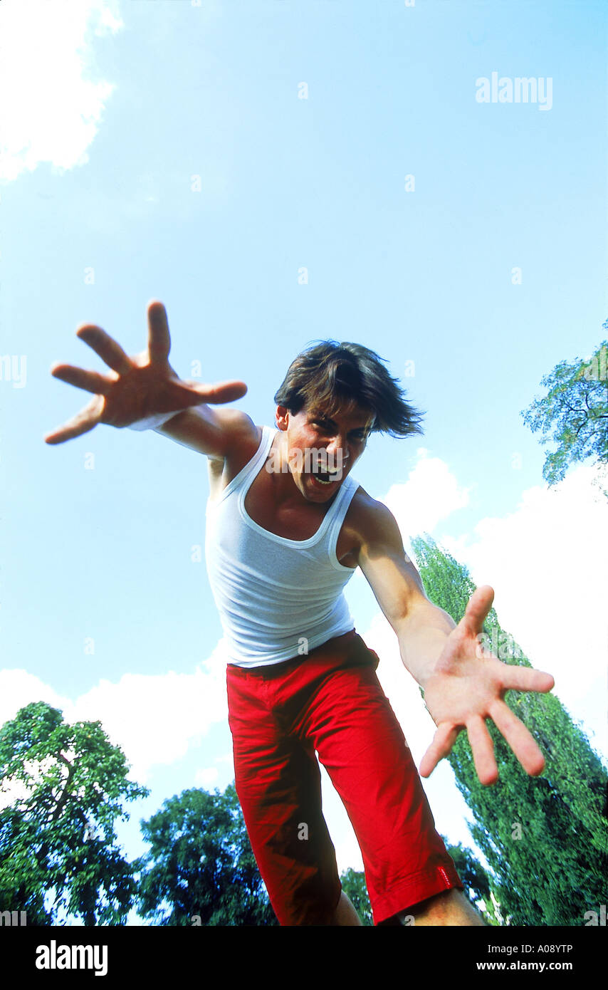 Low angle view of a young man bending down with his arms reaching out ...