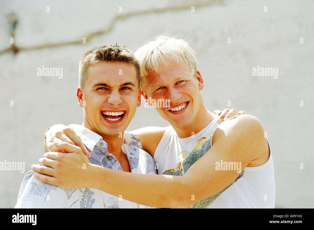 Portrait of two young men holding each other and smiling Stock Photo ...