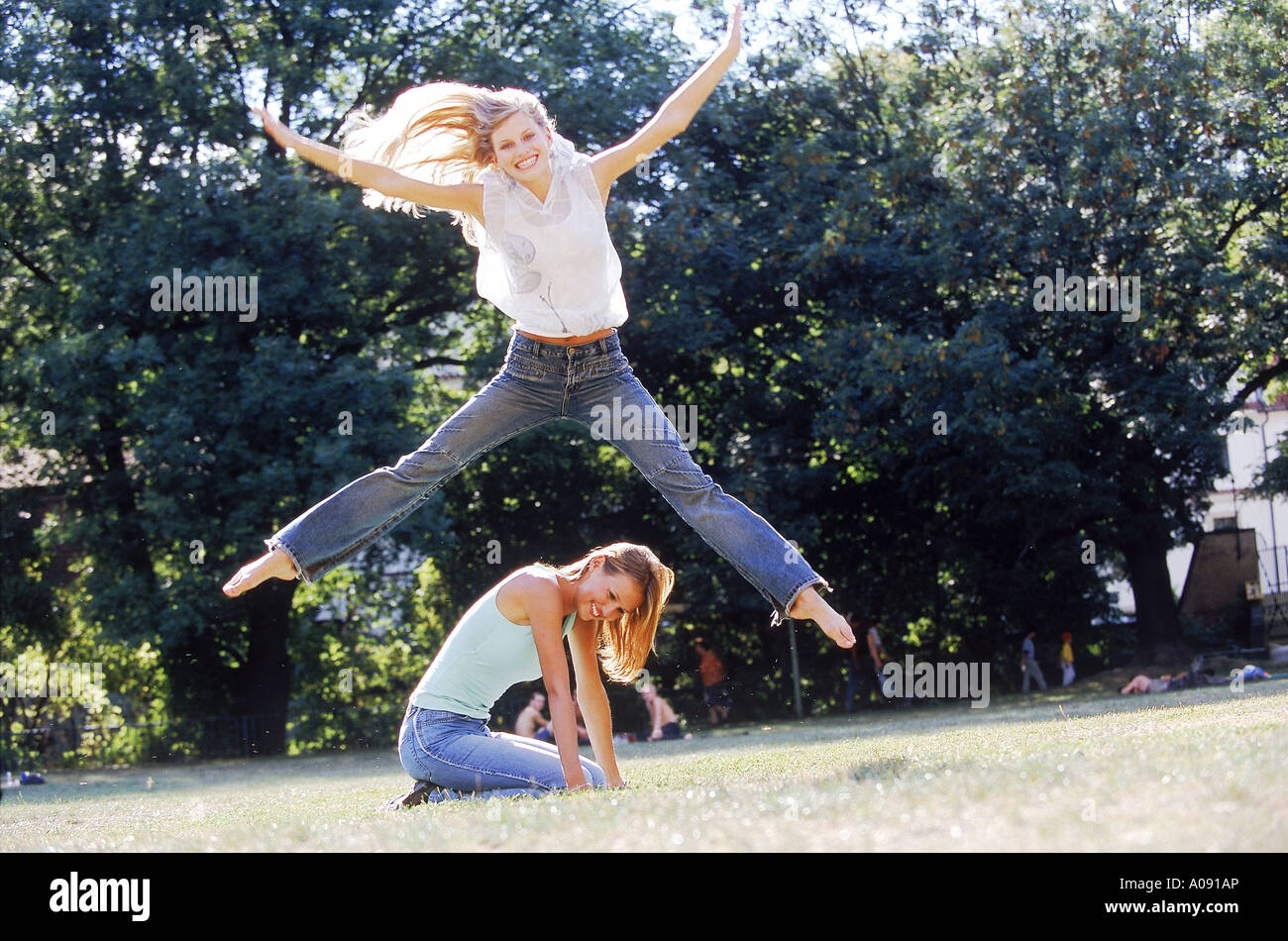 A woman jumping over another crouching on the ground Stock Photo - Alamy