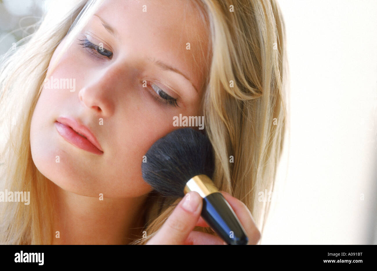Young woman applying color on her cheek Stock Photo - Alamy