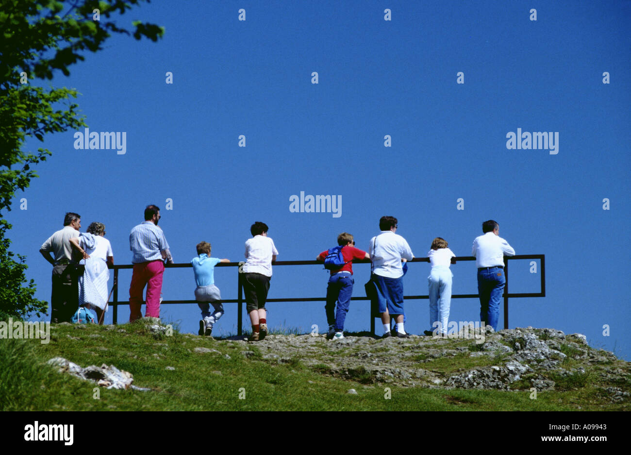People standing in a line looking to something handrail view ...