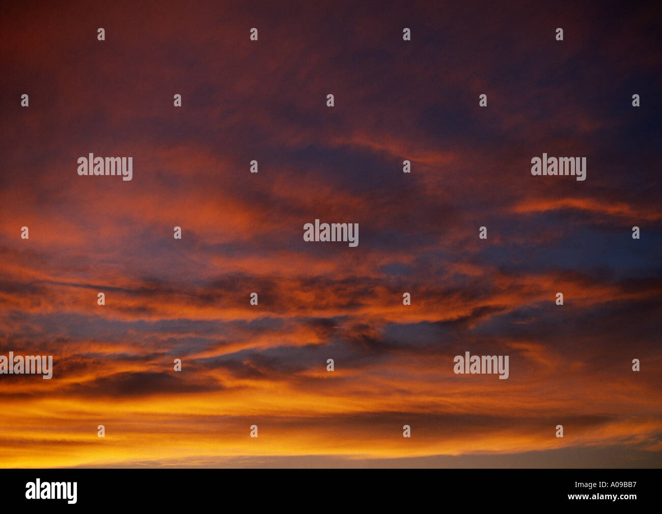 A dramatic skyscape at sunset marked by an orange and red glow and ...