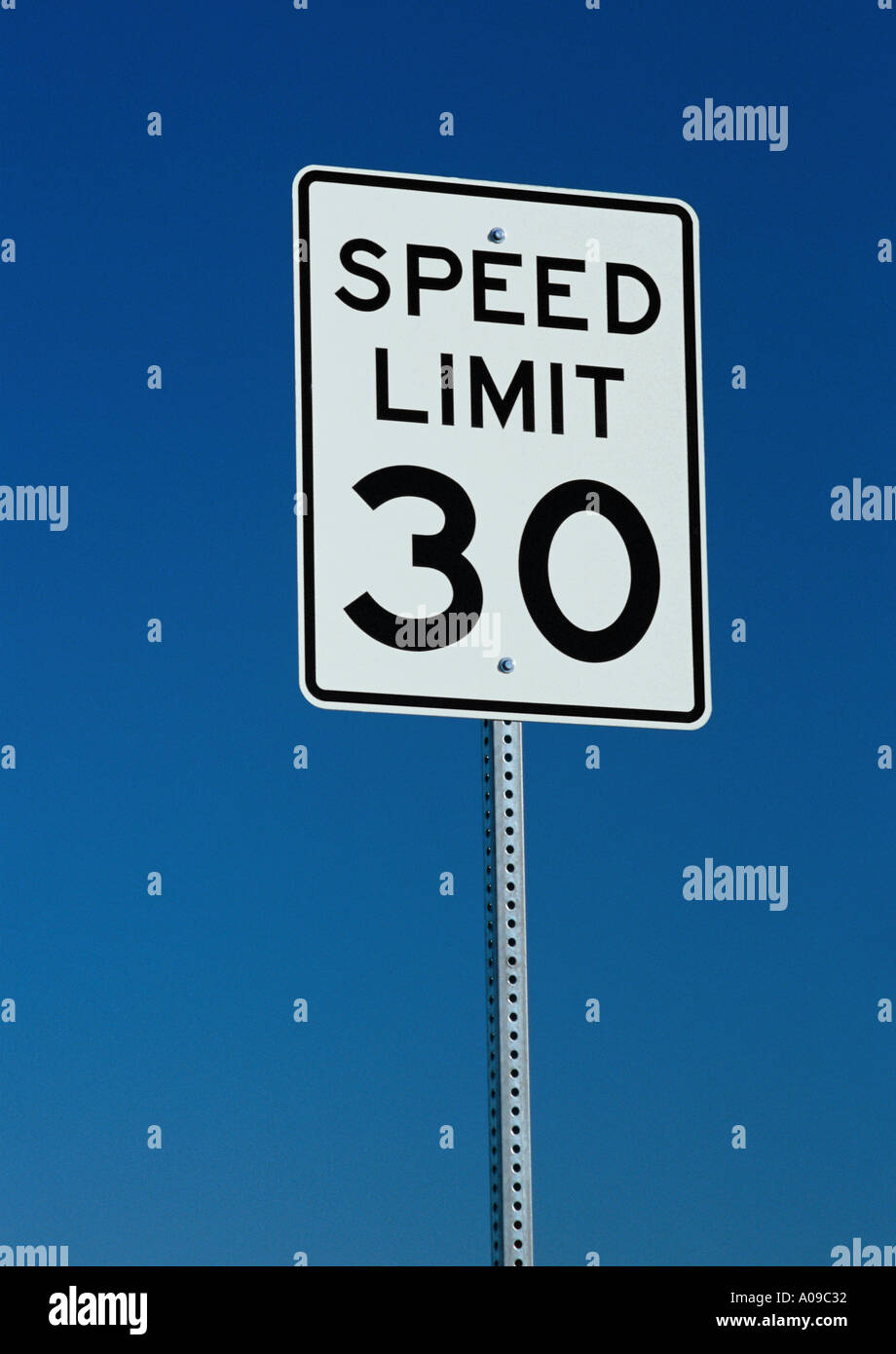 A black and white rectangular speed limit 30 road sign on a metal post ...