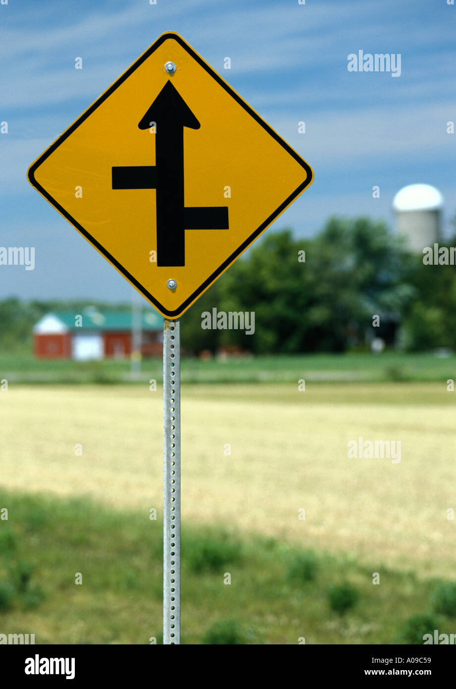 Diamond-shaped intersections ahead road sign with a farm in the ...