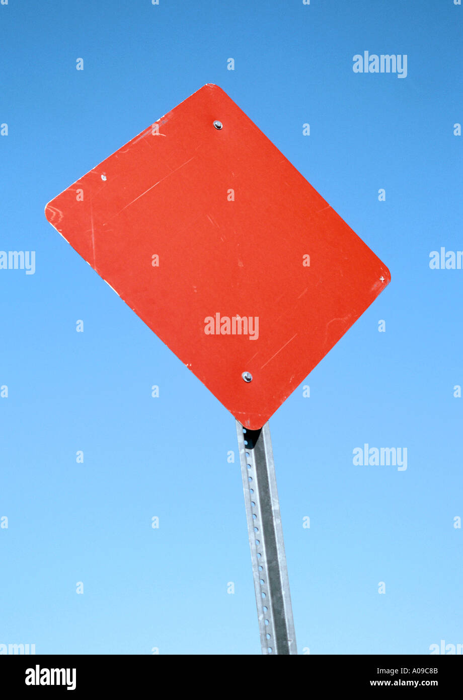 A red diamond shaped blank road sign on a metal post against a ...