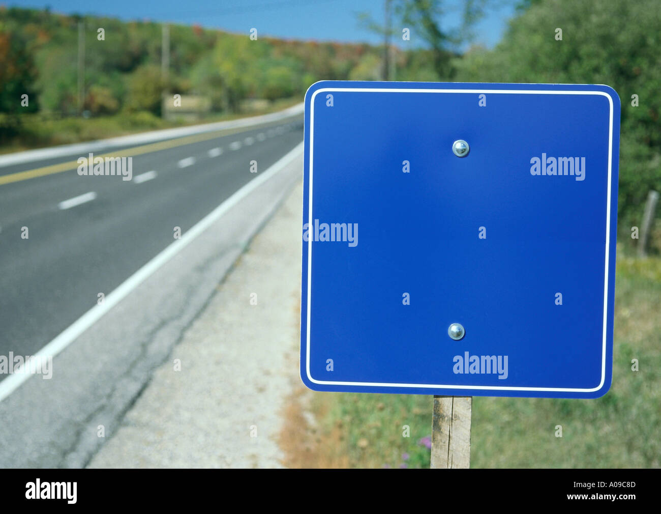 A blue and white square blank road sign on a metal post beside the ...