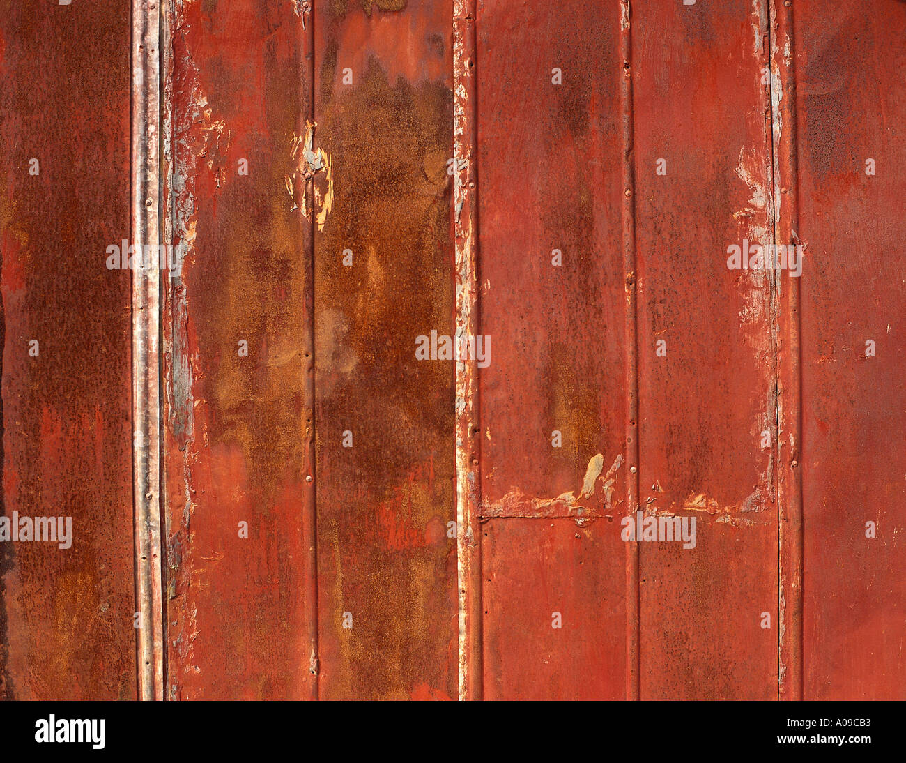 A close up of aged and weathered rusted metal siding with worn red ...