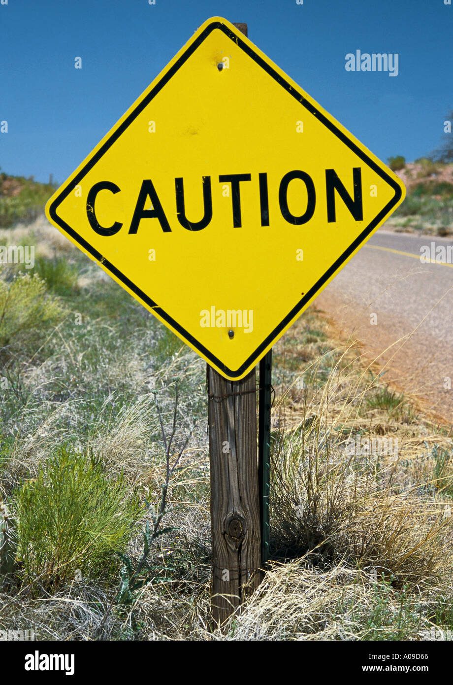 Yellow diamond-shaped caution road sign on the side of a rural highway ...
