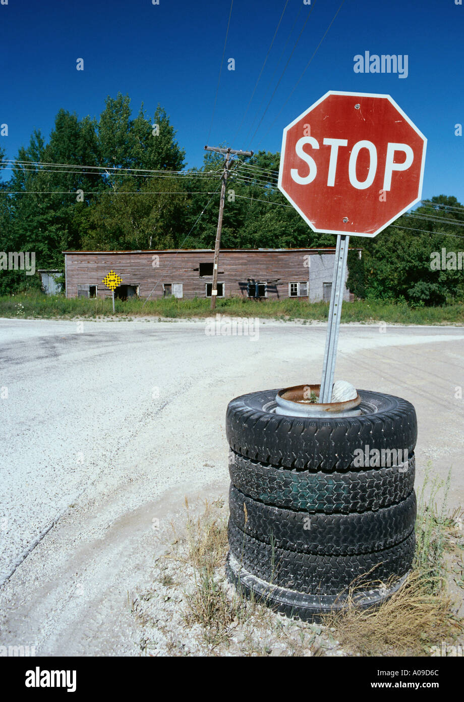 STOP sign on post sticking out of stack of tires at rural intersection ...