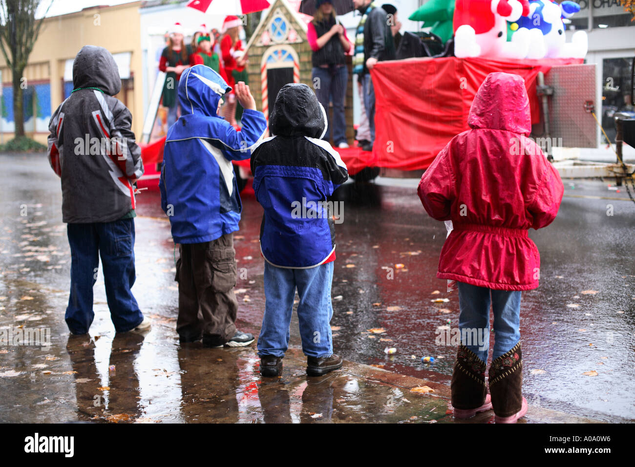 Four children stand in the rain watching a parade Stock Photo - Alamy