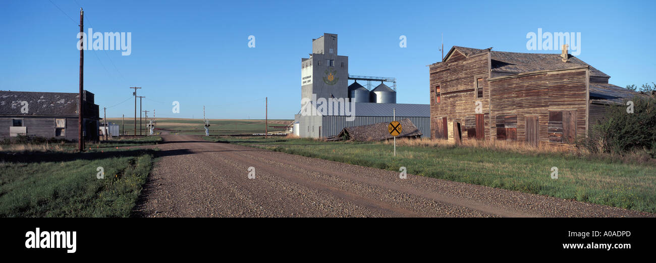 Gravel country road between abandoned buildings and grain elevator ...
