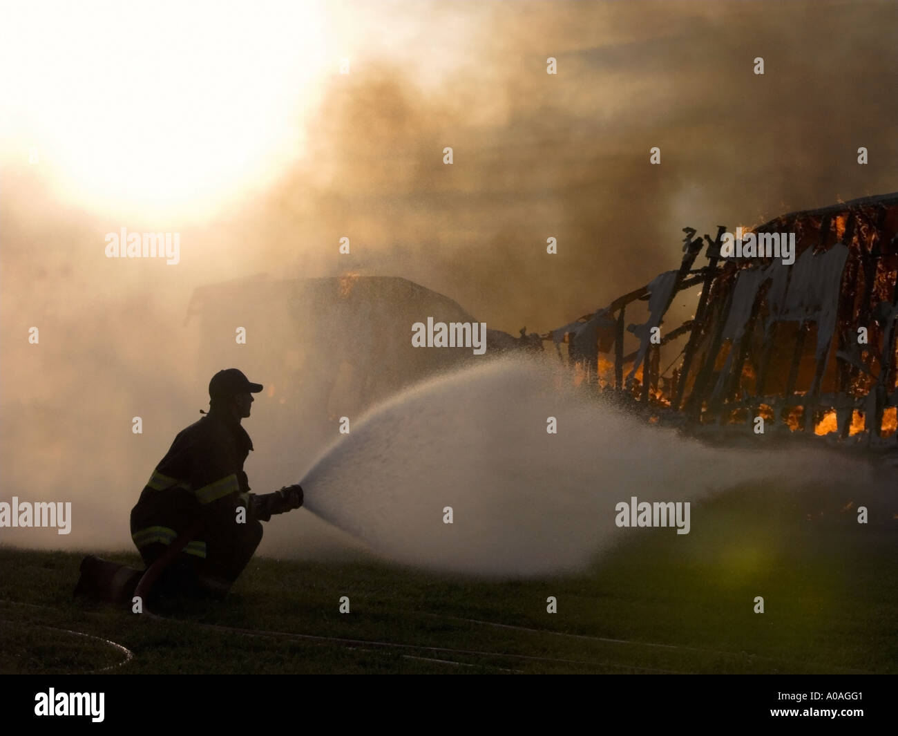 Firefighter spraying water on burning house trailer Stock Photo - Alamy