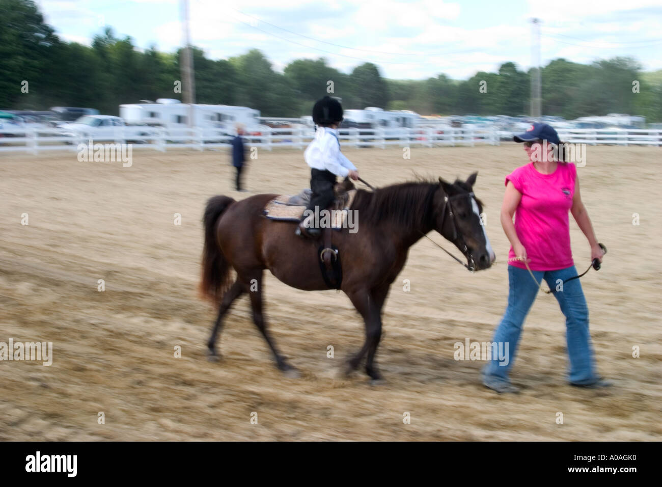 Woman leading a young child wearing a helmet and riding clothes on a ...