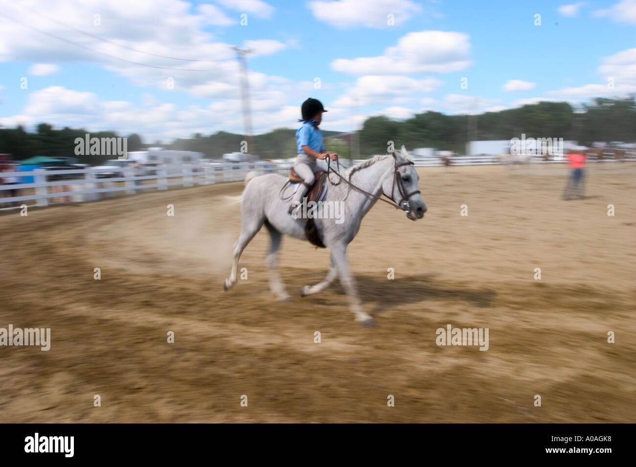 Young girl wearing a helmet and riding clothes riding her horse in a ...