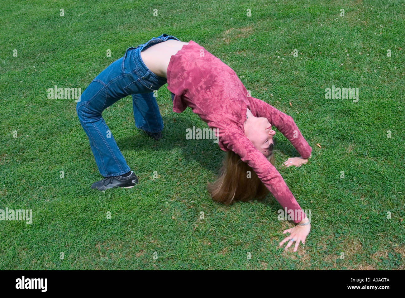 Young woman with long hair and wearing glasses lying in a contorted ...