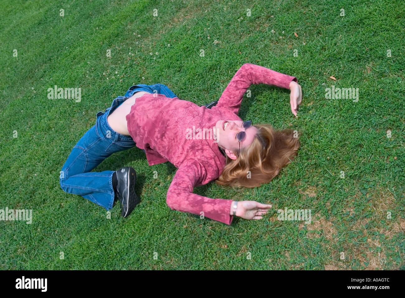Young woman with long hair and wearing glasses lying in a contorted ...