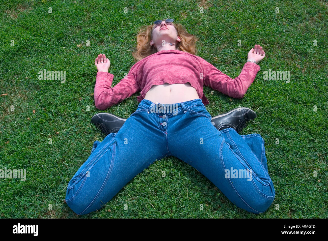 Young woman with long hair and wearing glasses lying in a contorted ...
