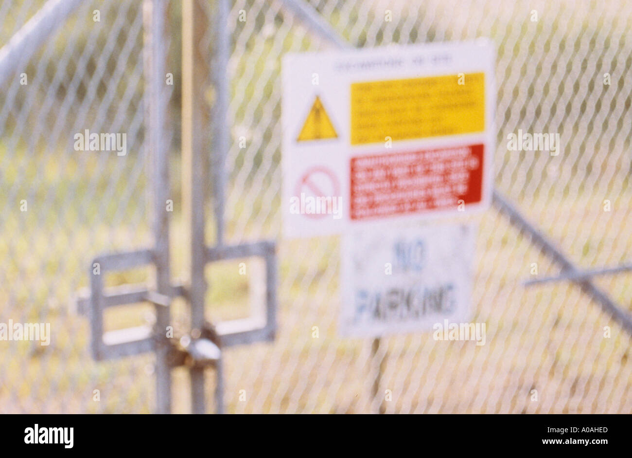 Defocussed padlocked galvanised wire mesh fence with warning and ...