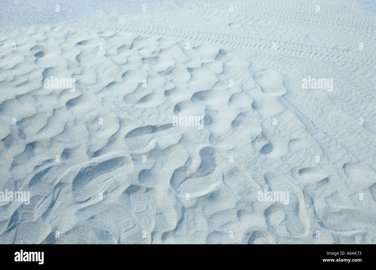 Soft dry white powdery sand showing ripples and footprints and tyre ...