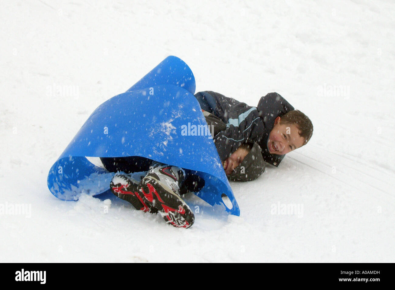 Two young boys, brother, sledding with crazy carpet, crashing and ...