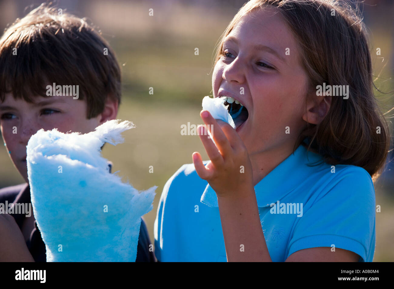 Siblings eating blue cotton candy Stock Photo - Alamy