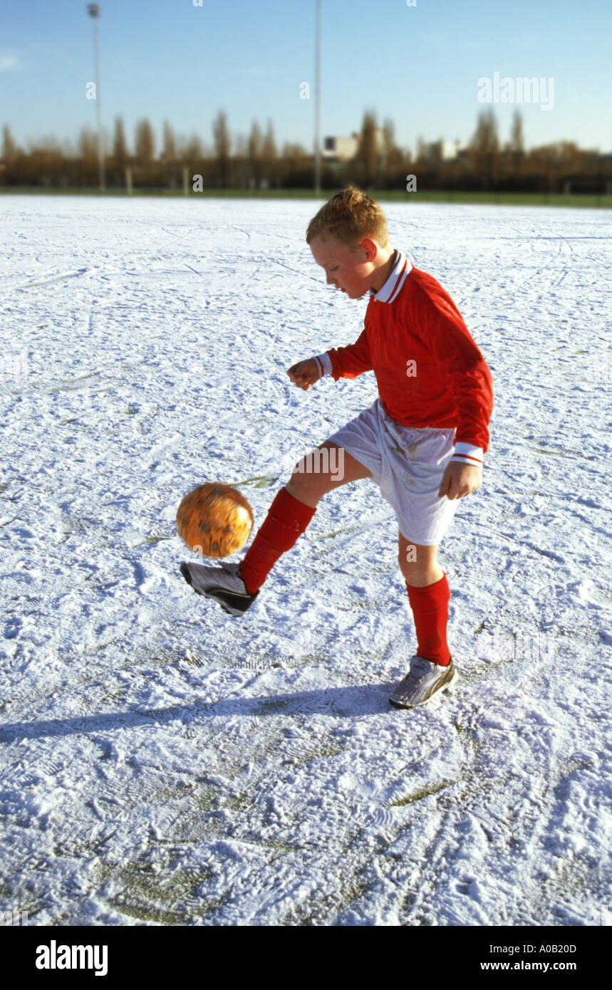 Young boy playing football in snow Stock Photo - Alamy