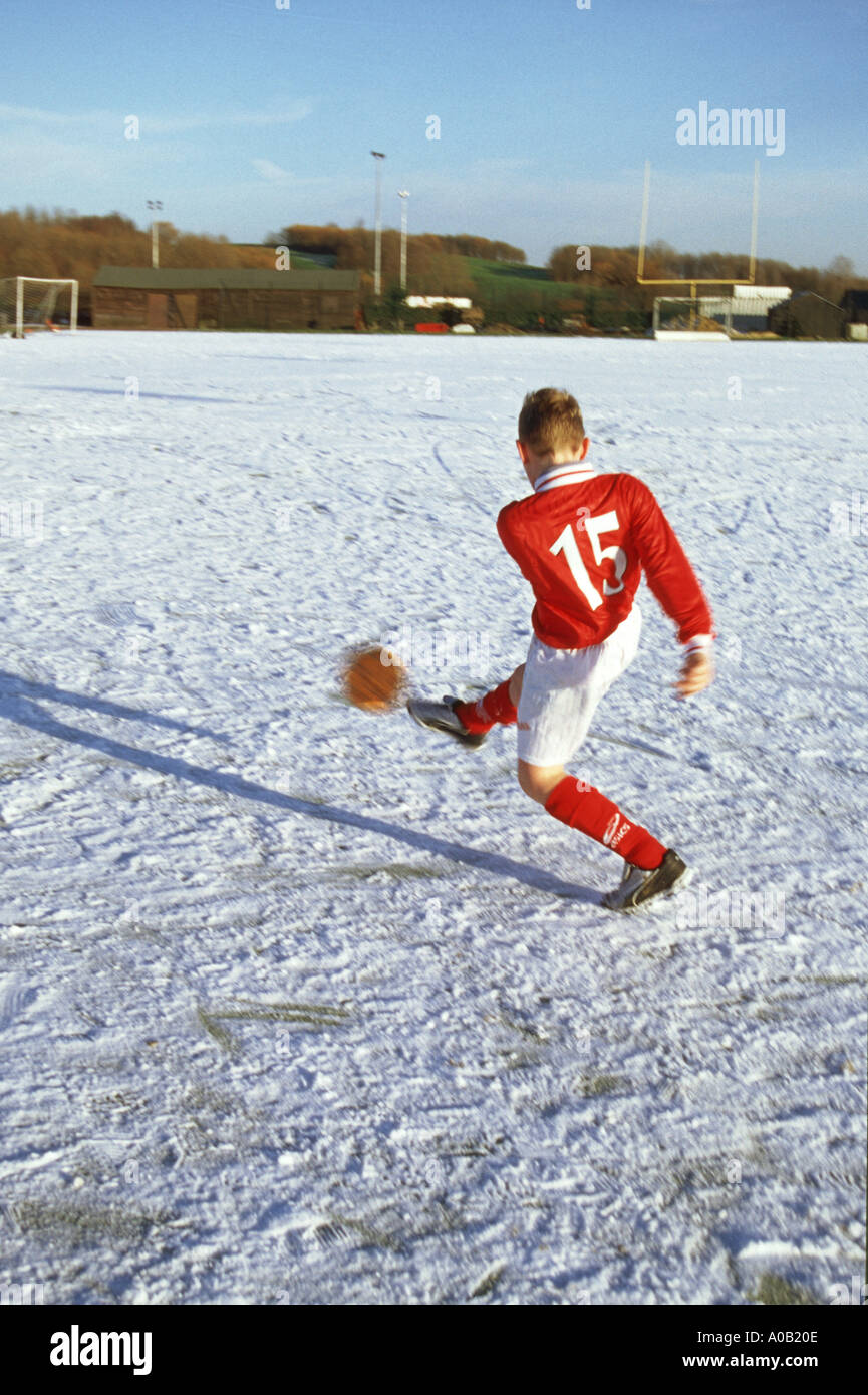 Young boy playing football in snow Stock Photo - Alamy