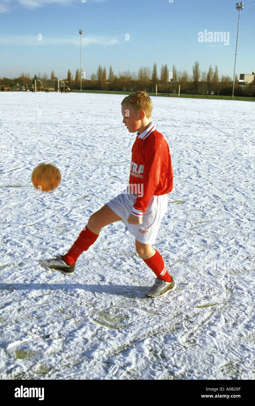 Young boy playing football in snow Stock Photo - Alamy