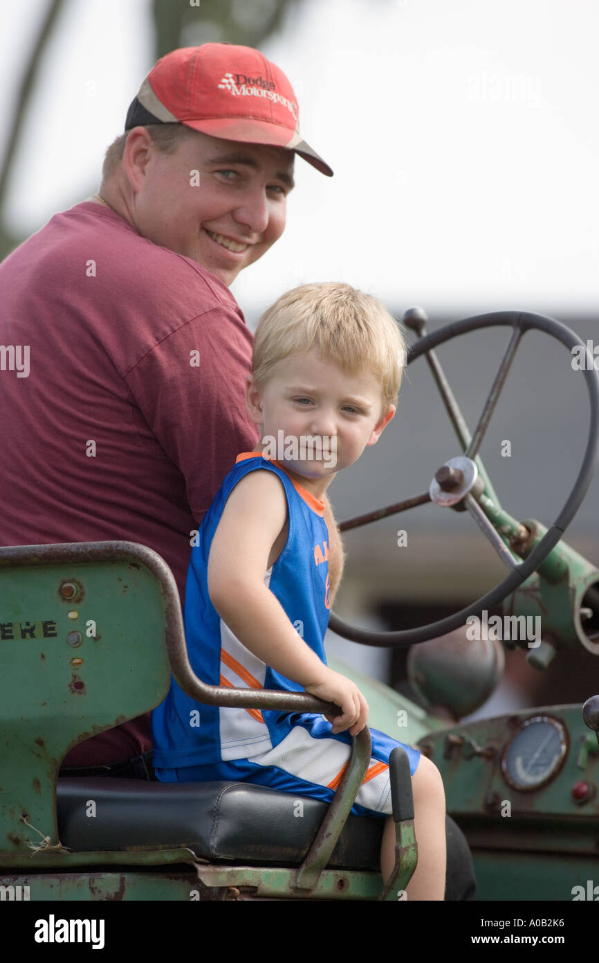 Father and son riding on antique tractor Stock Photo - Alamy