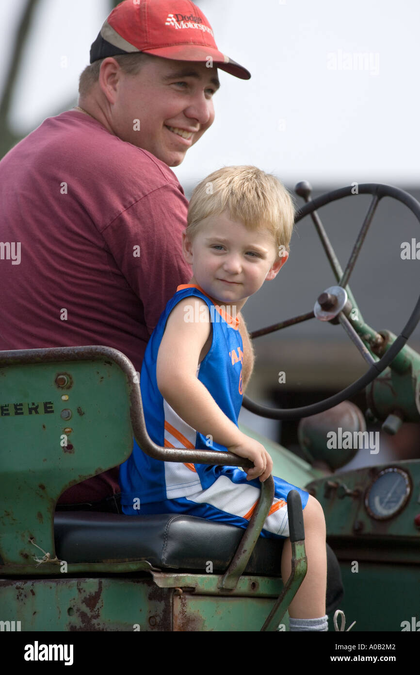 Father and son riding on antique tractor Stock Photo - Alamy