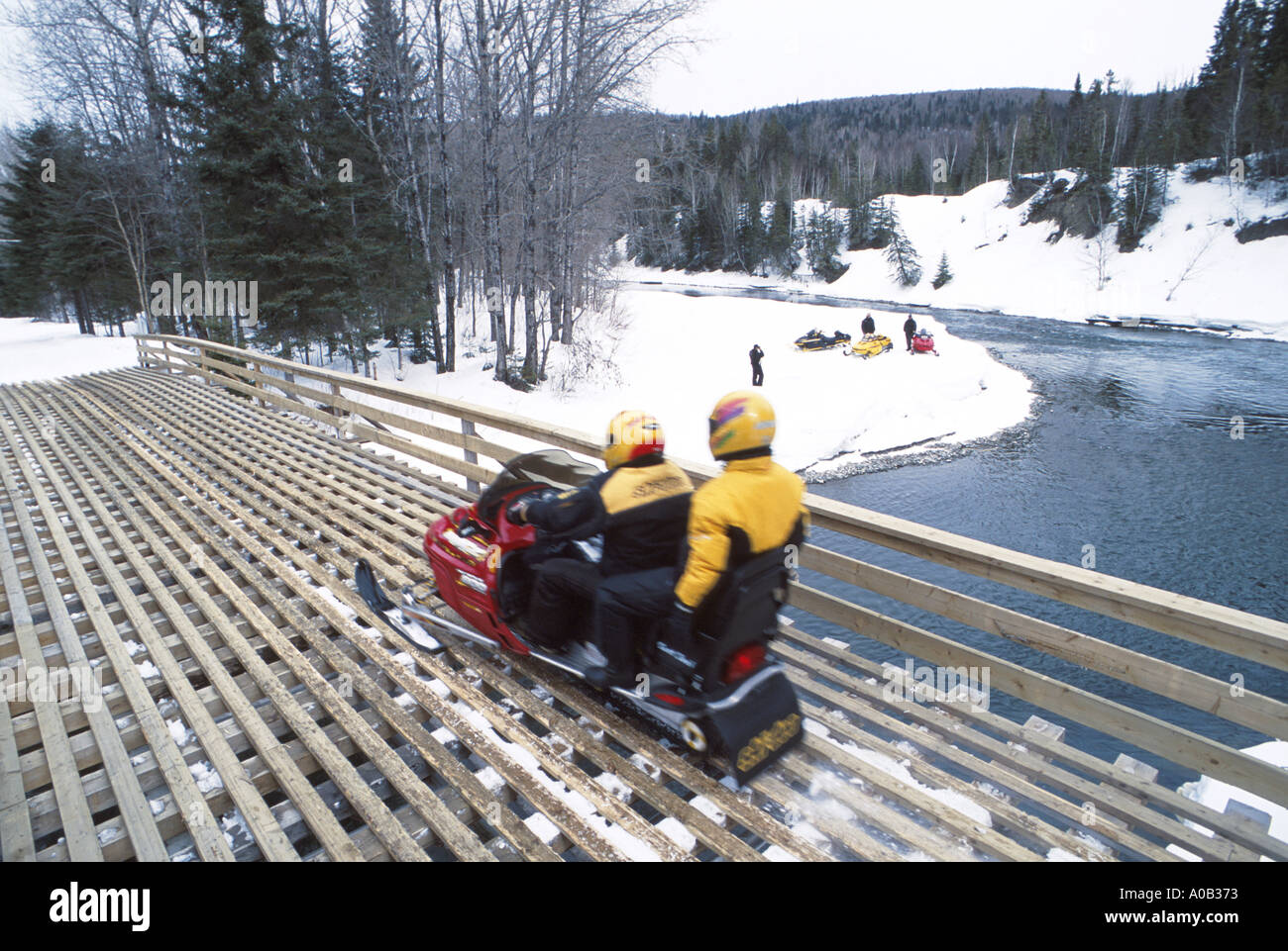 snowmobiles in winter crossing a bridge over open water in New ...
