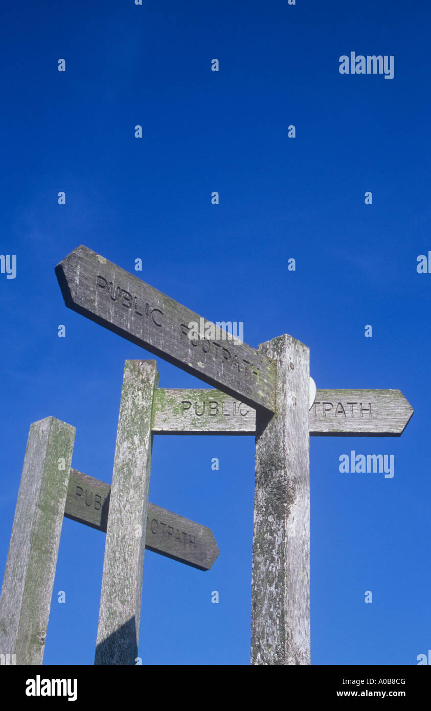 Three wooden fingerpost signs close together under clear blue sky ...