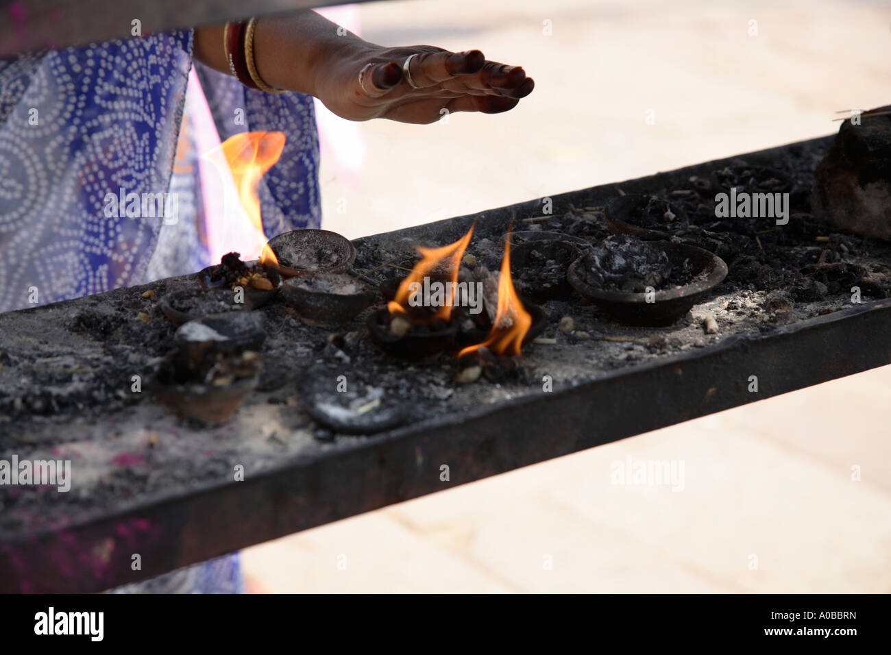 Indian woman passes her hand over a flame as a sign of Hindu worshipful ...