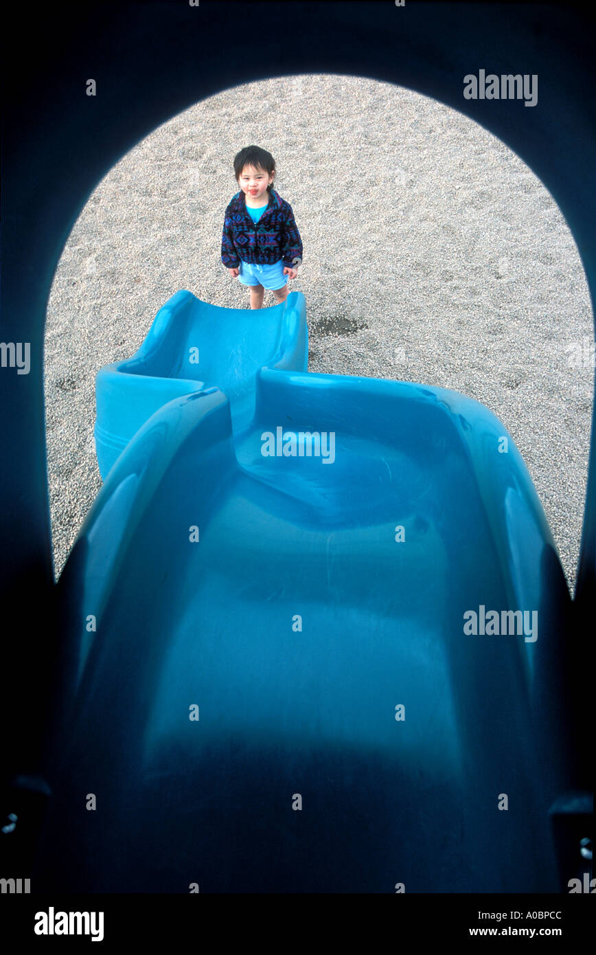 Young girl playing on a sliding board at a playground Stock Photo - Alamy