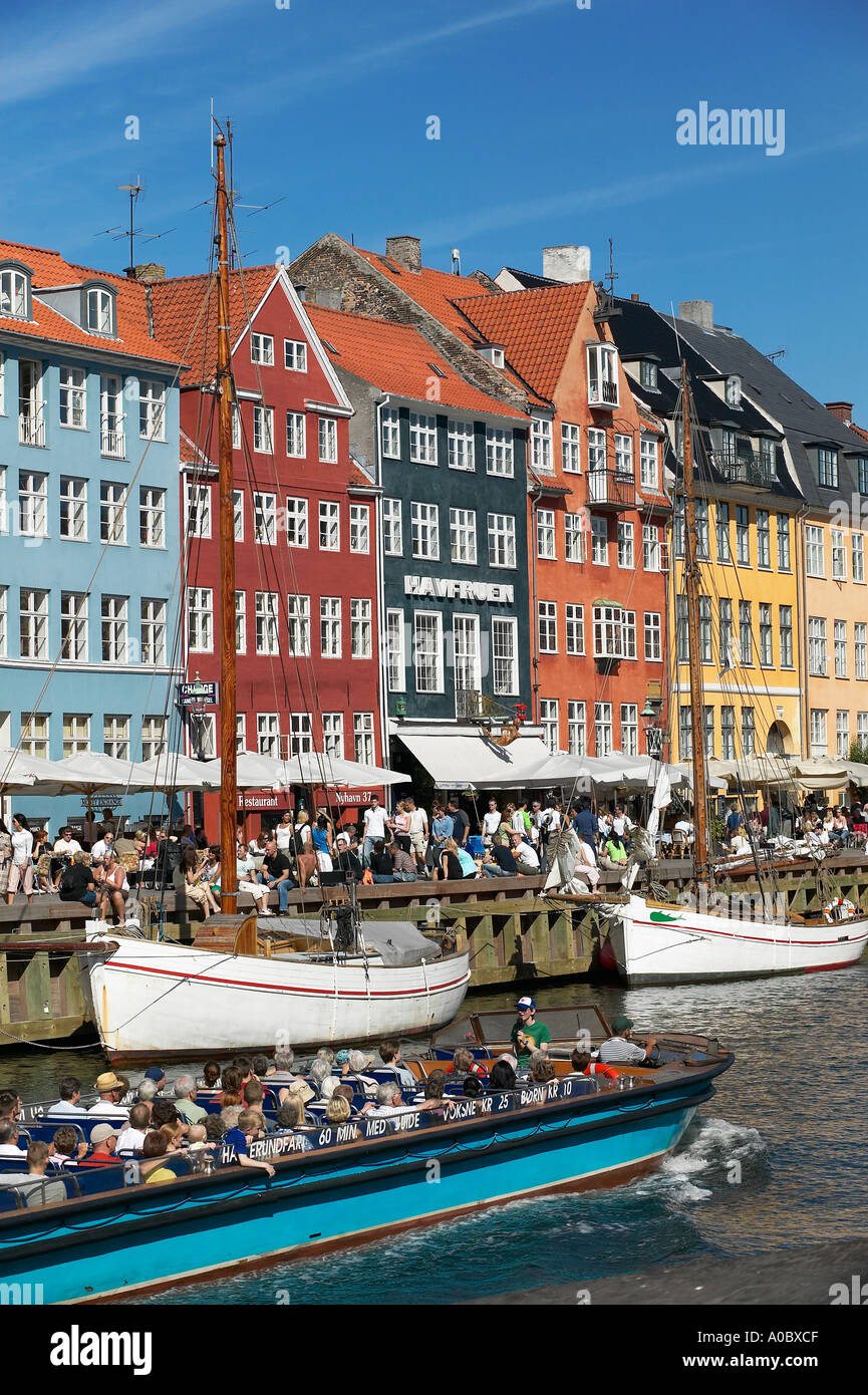 Sightseeing tour boat on Nyhavn canal and quayside cafe terraces ...
