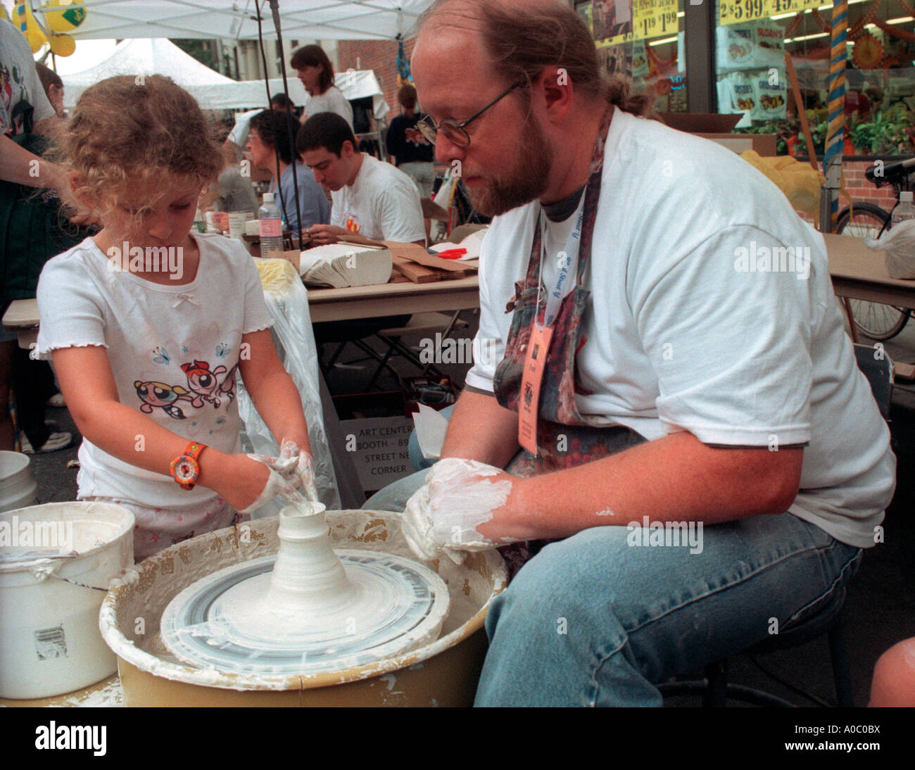Five year old girl is instructed in throwing a pot on a potter s wheel ...