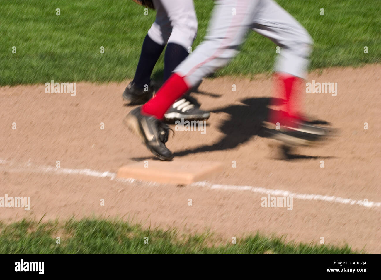 Preteen boy rounding first base after hitting the ball during a Little ...