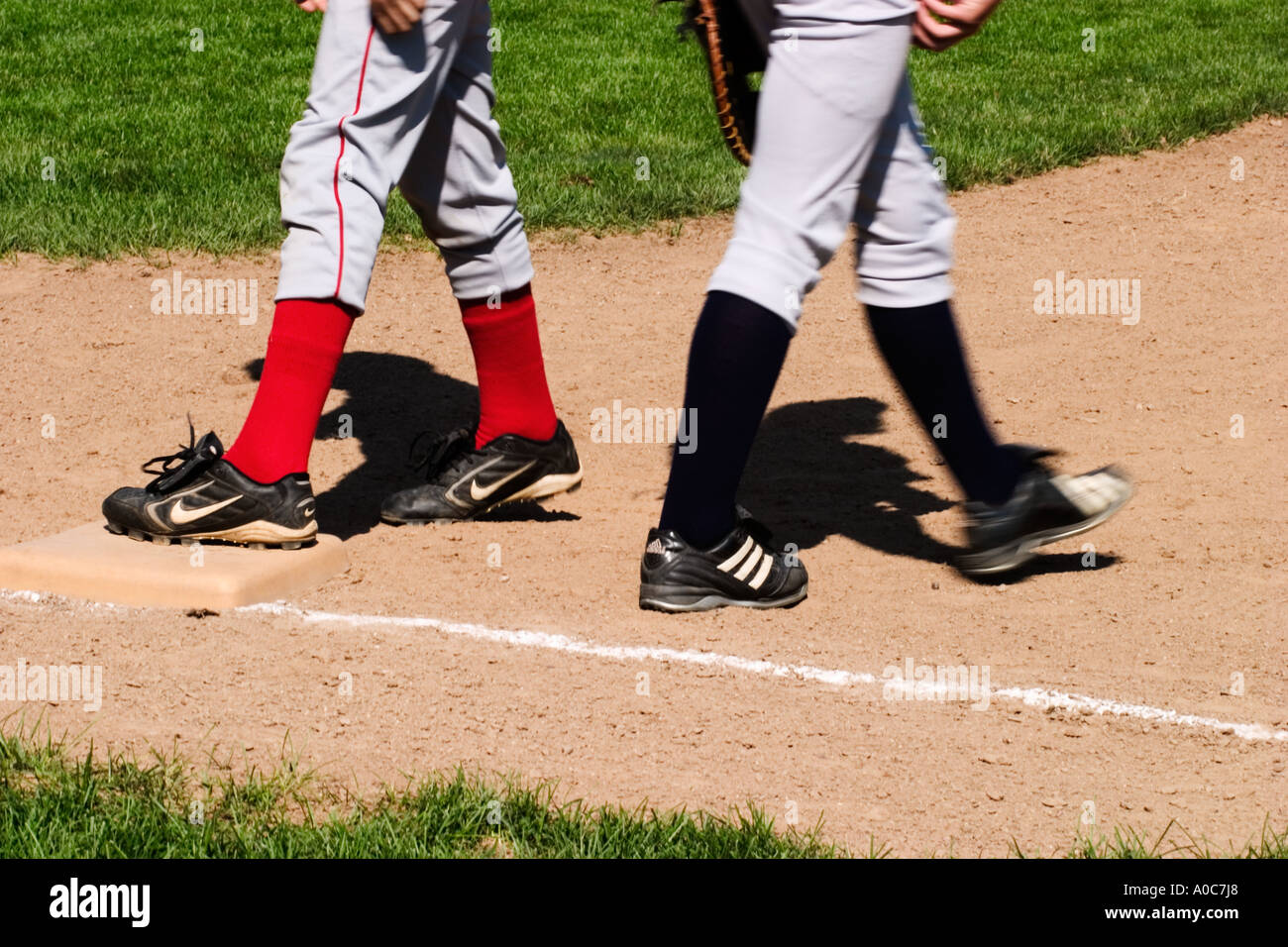 Preteen boy standing on first base next to the boy playing first base ...