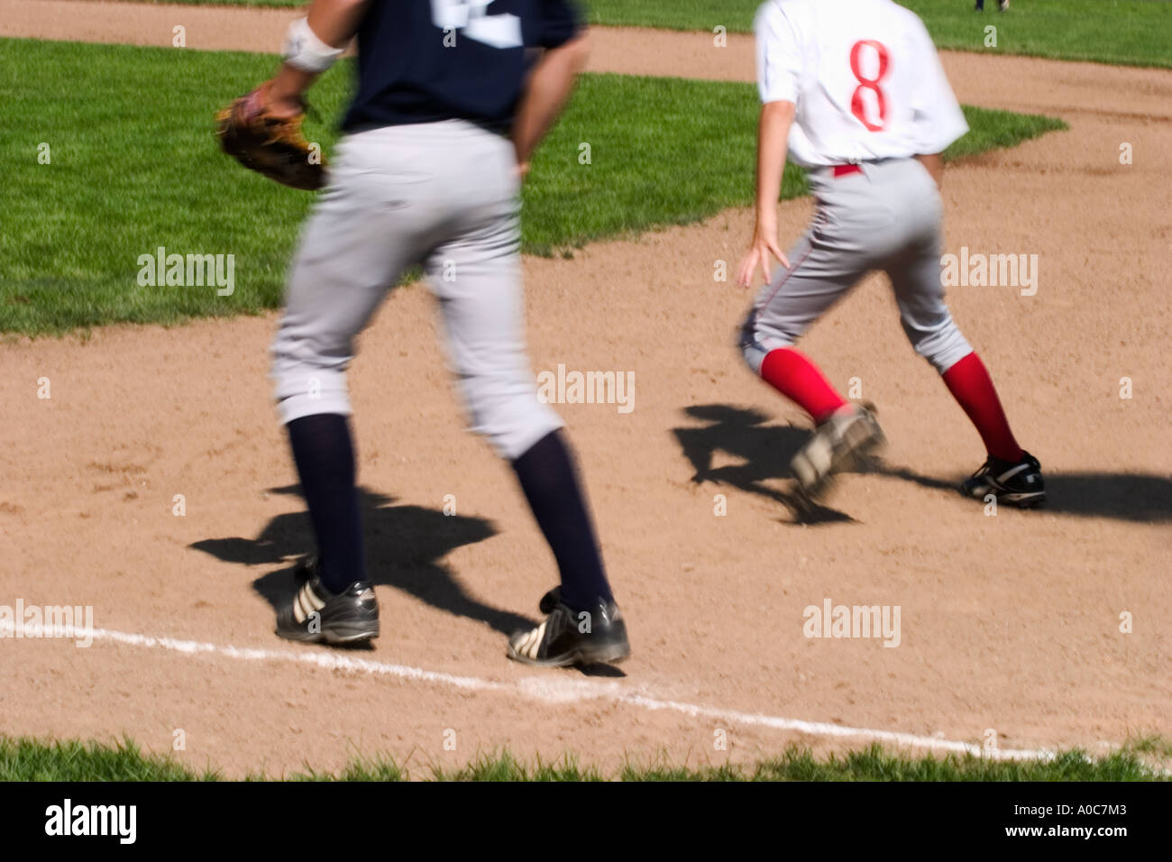 Preteen boy taking a lead off of first base with the boy playing first ...