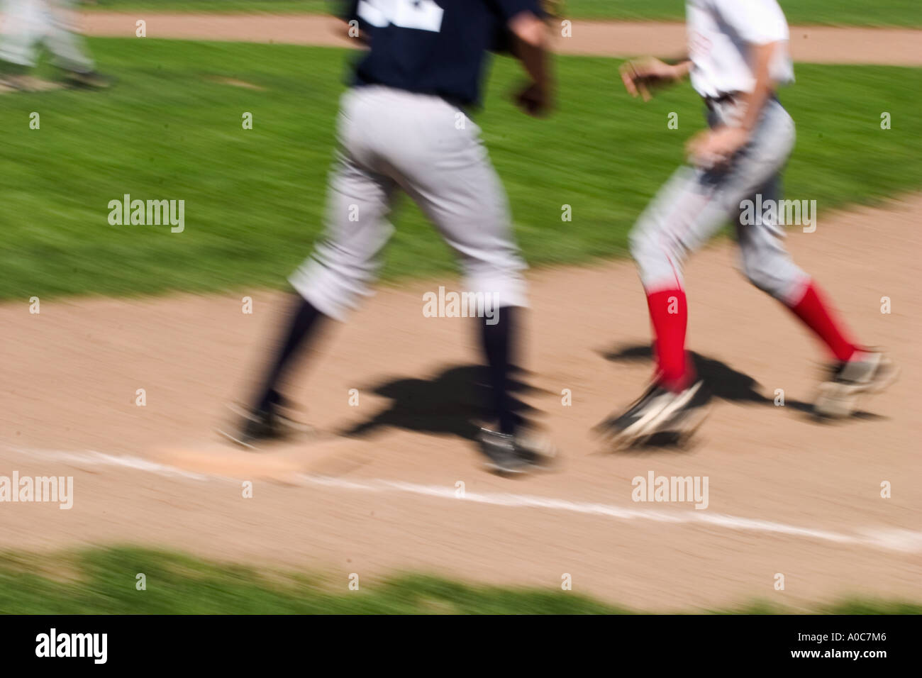 Preteen boy running back to first base while the boy playing first base ...