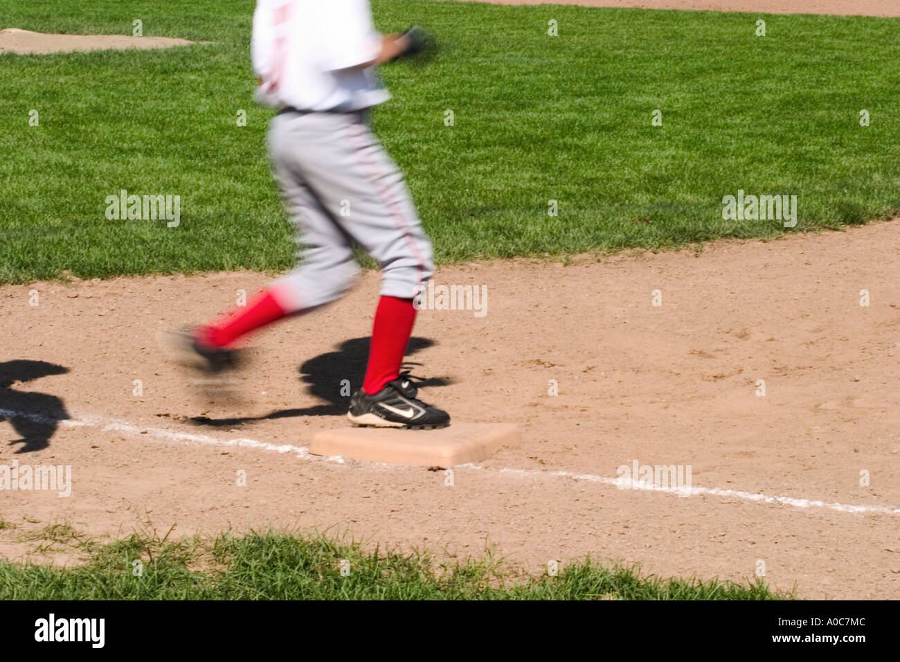 Preteen boy rounding first base after hitting the ball during a Little ...