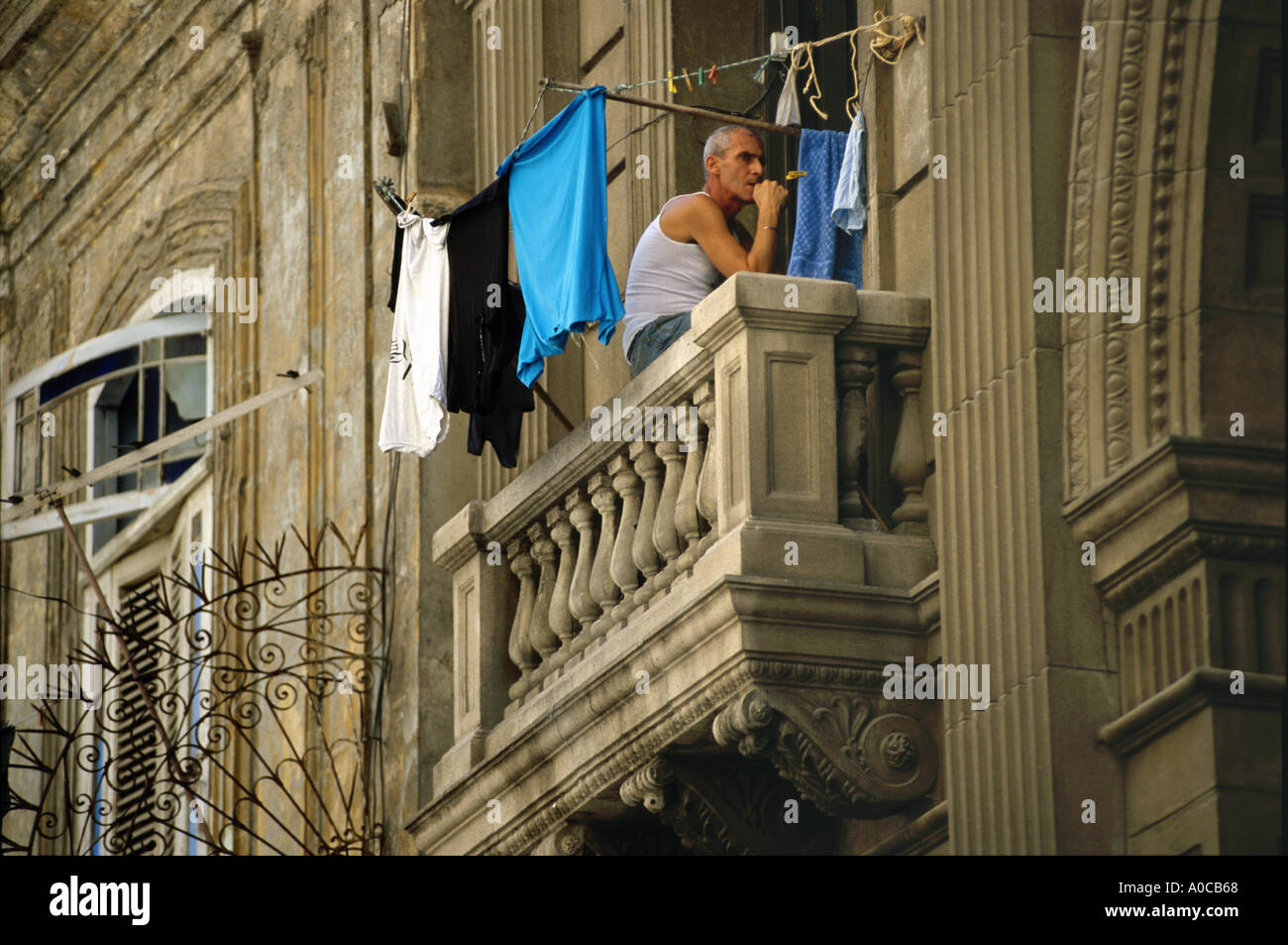 Man sits on balcony in Habana Vieja Stock Photo - Alamy