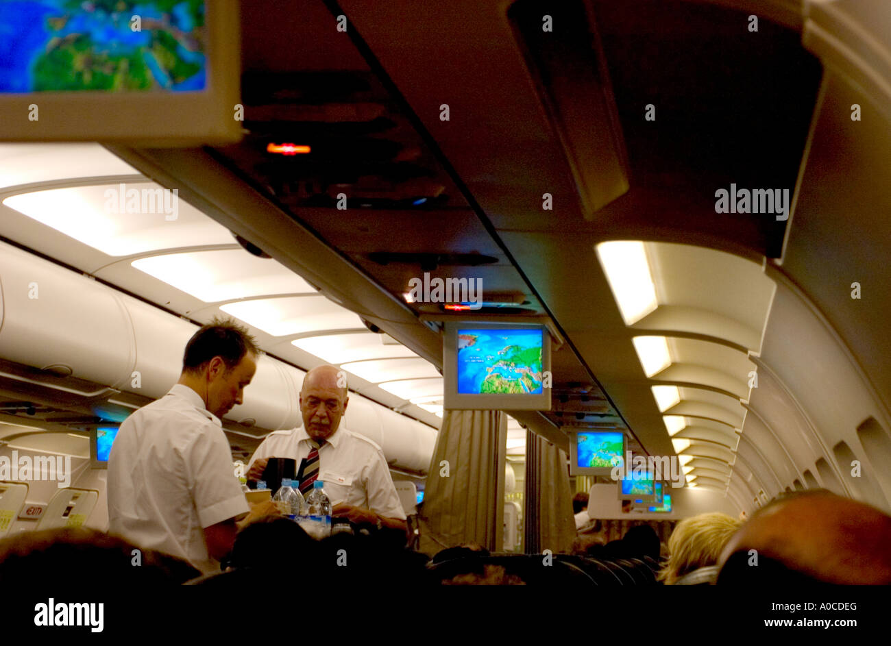 inside airplane and mini tv monitor with steward crew members Stock ...