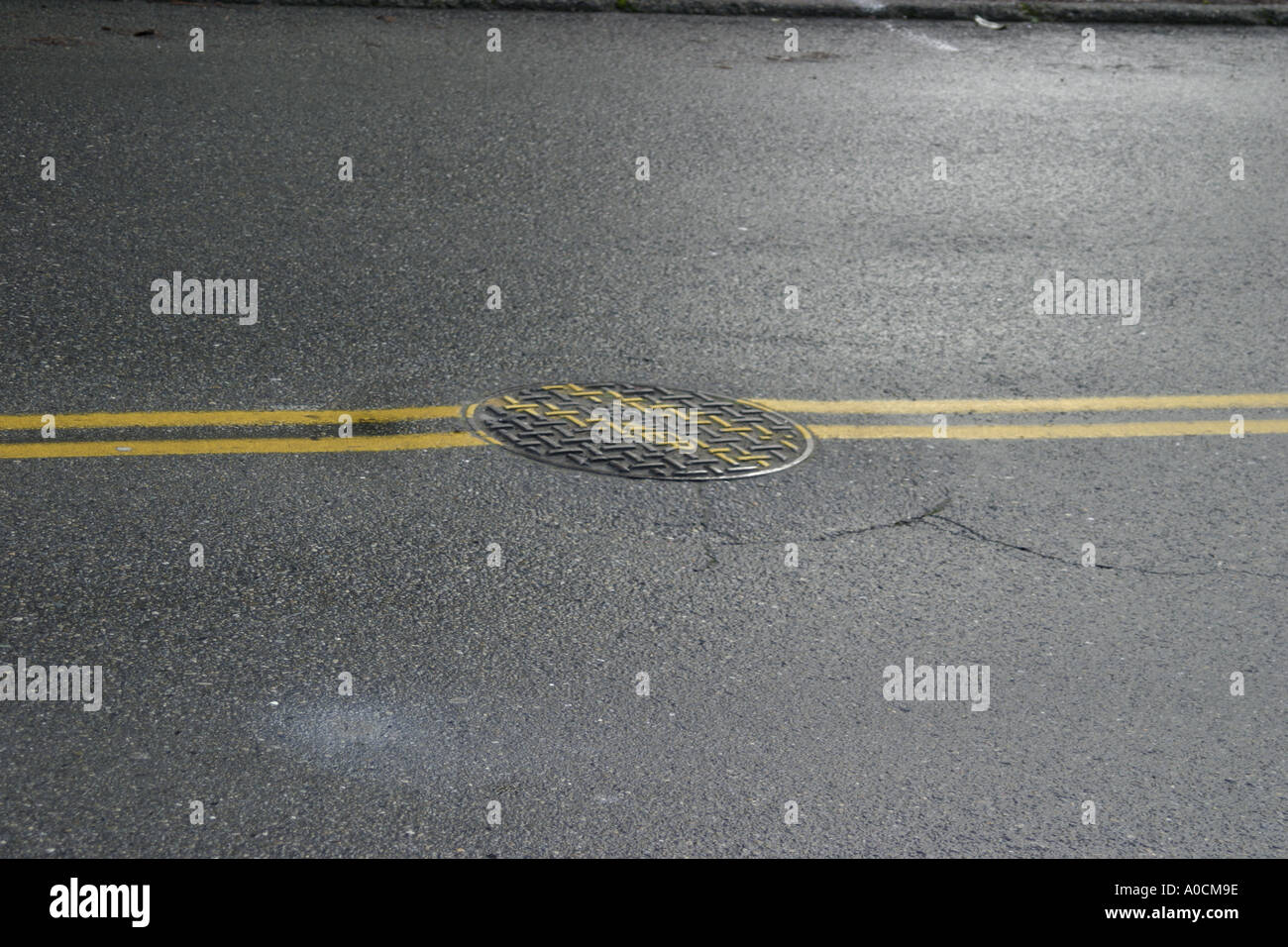 manhole cover turned crosswise to painted double yellow line on street ...