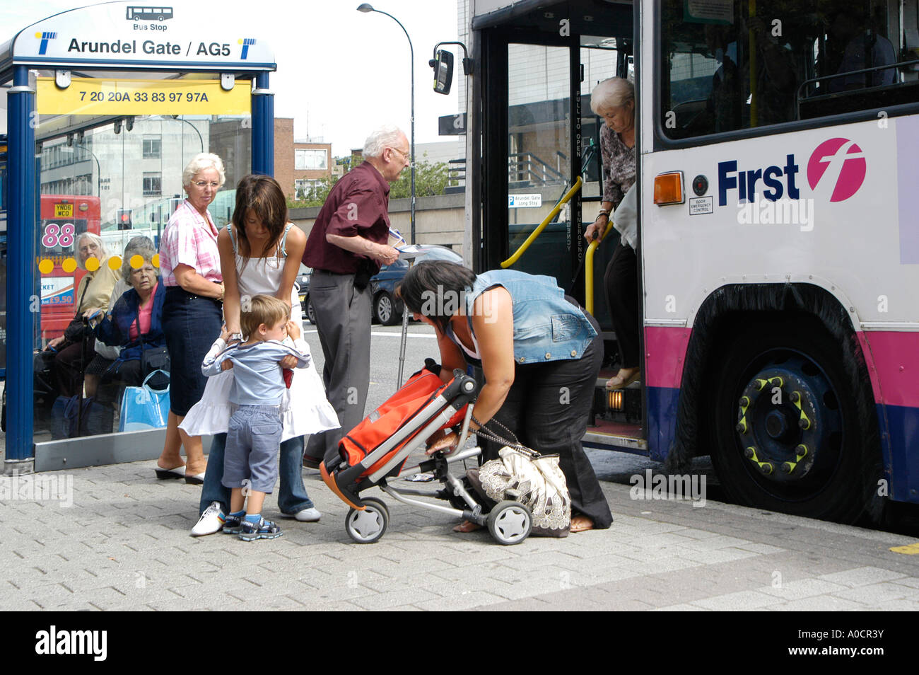 passengers boarding a first bus at a bus stop in an english city centre ...